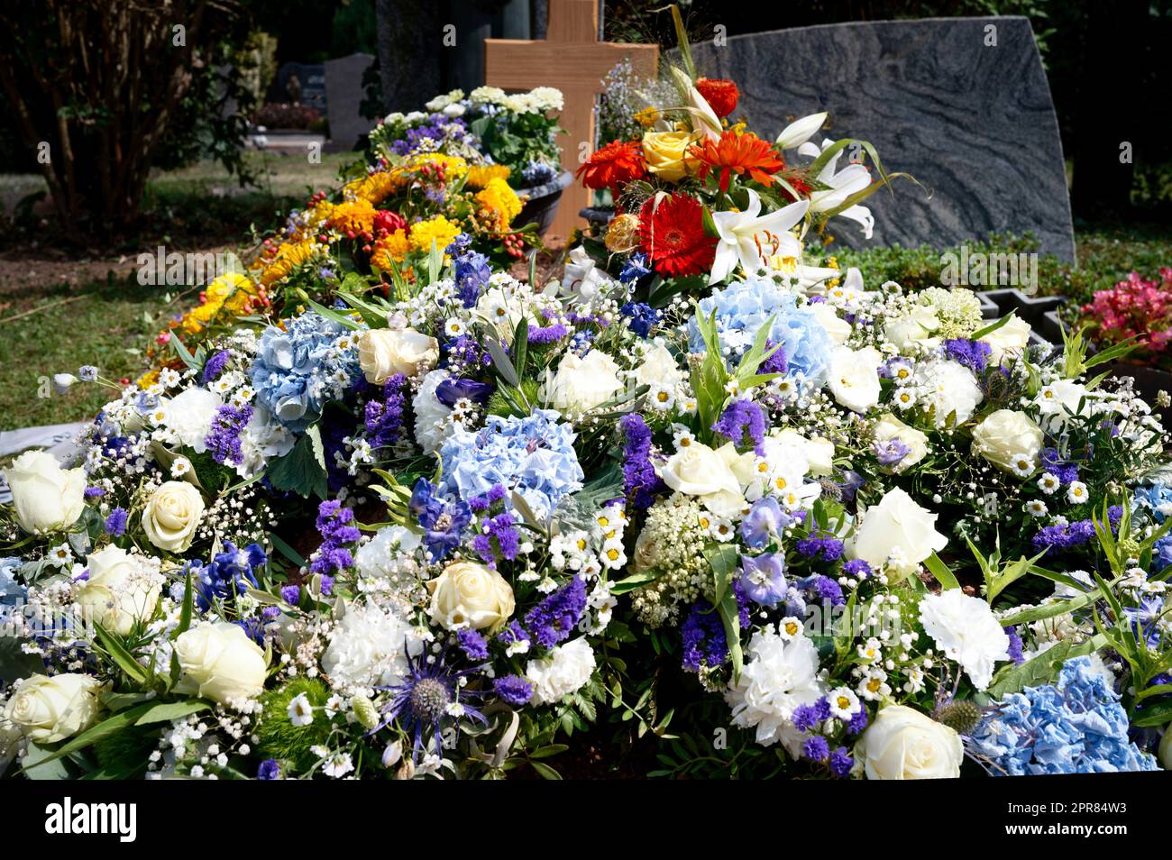 many blue-white and red orange mourning flowers after a funeral on a ...