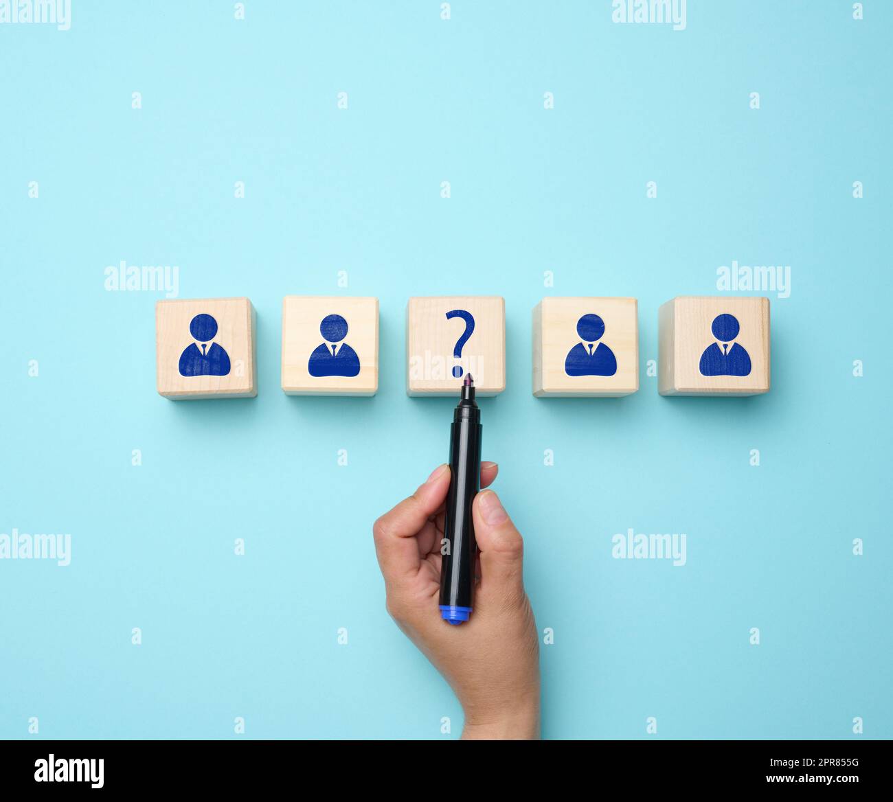 Wooden figures of men and a woman's hand drew a question mark with a ...