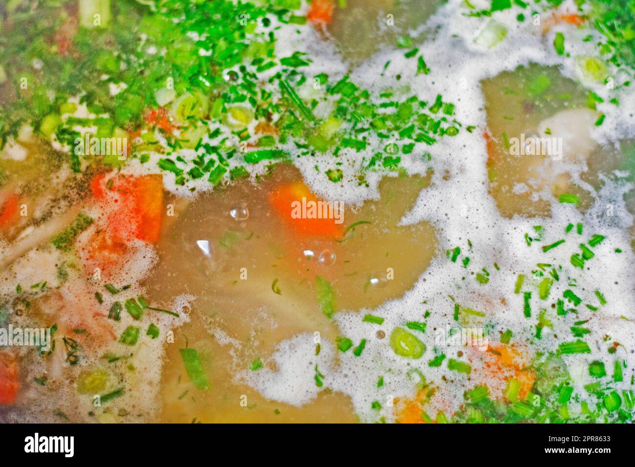 abstract background of boiling chicken soup with greens and carrots ...