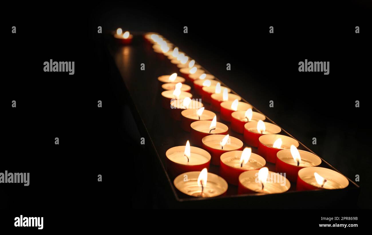 votive candles with flame lit during the mass of the faithful inside ...