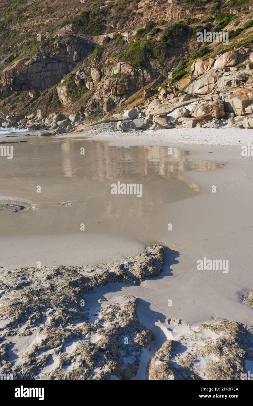 A rocky coastline at a beach in Cape Town with mountains in the ...