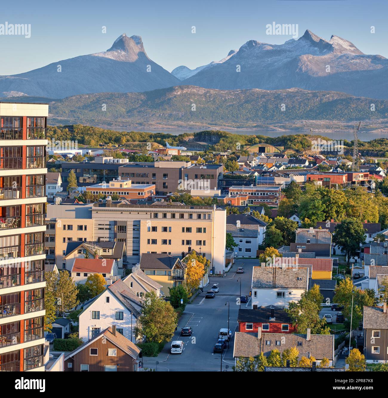 A small city surrounded by nature with a mountain in the background. A ...