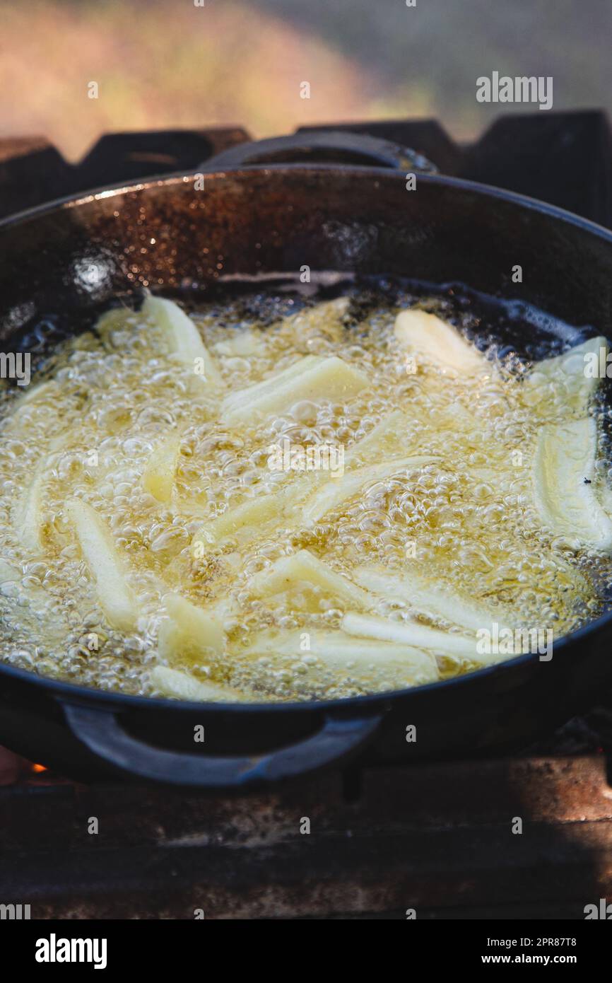 the process of cooking french fries on a fire in a cauldron. time for a ...