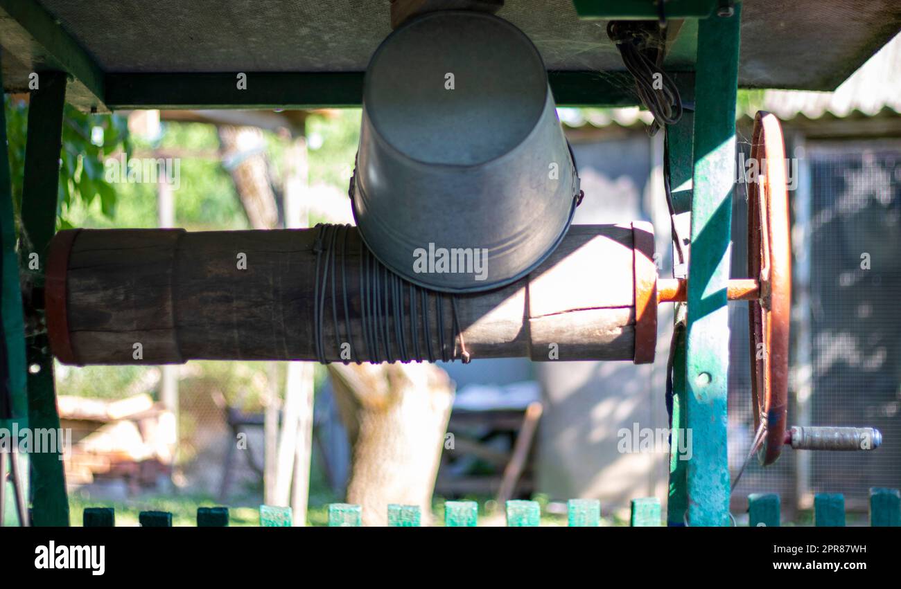 A well with a bucket in a European village. Sunny day. Metal bucket for ...
