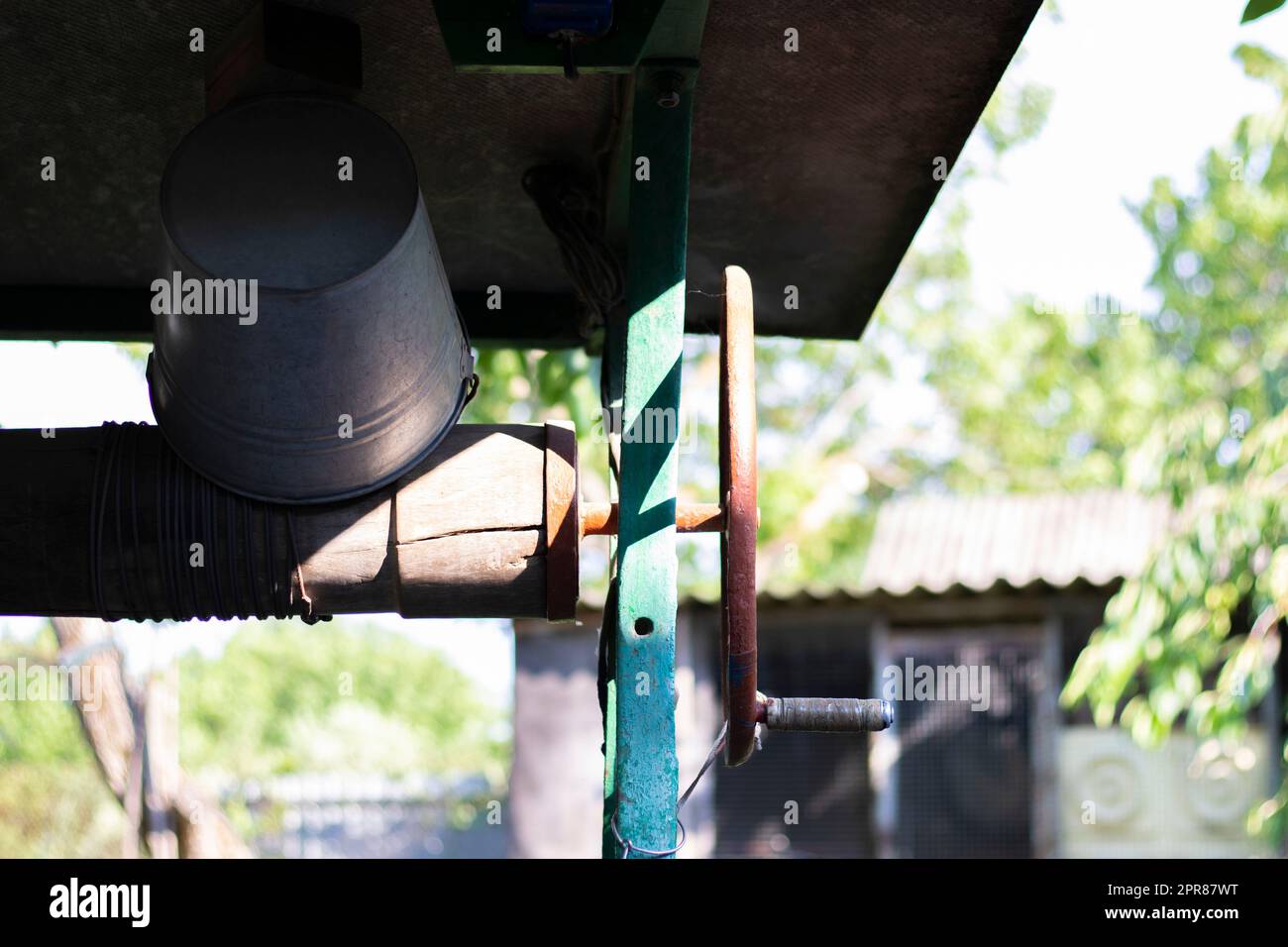 A well with a bucket in a European village. Sunny day. Metal bucket for ...