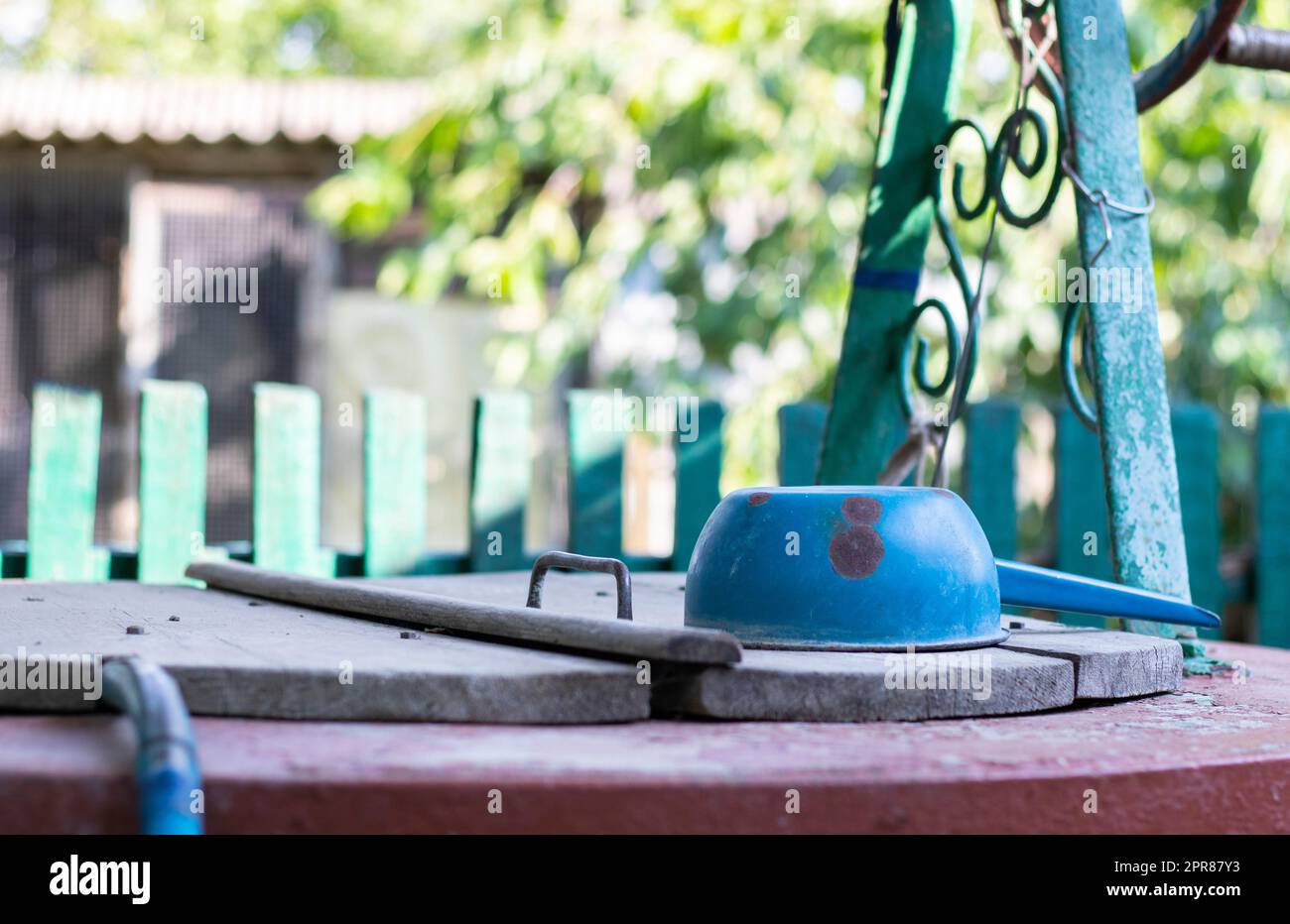 A well with a bucket in a European village. Sunny day. Metal bucket for ...