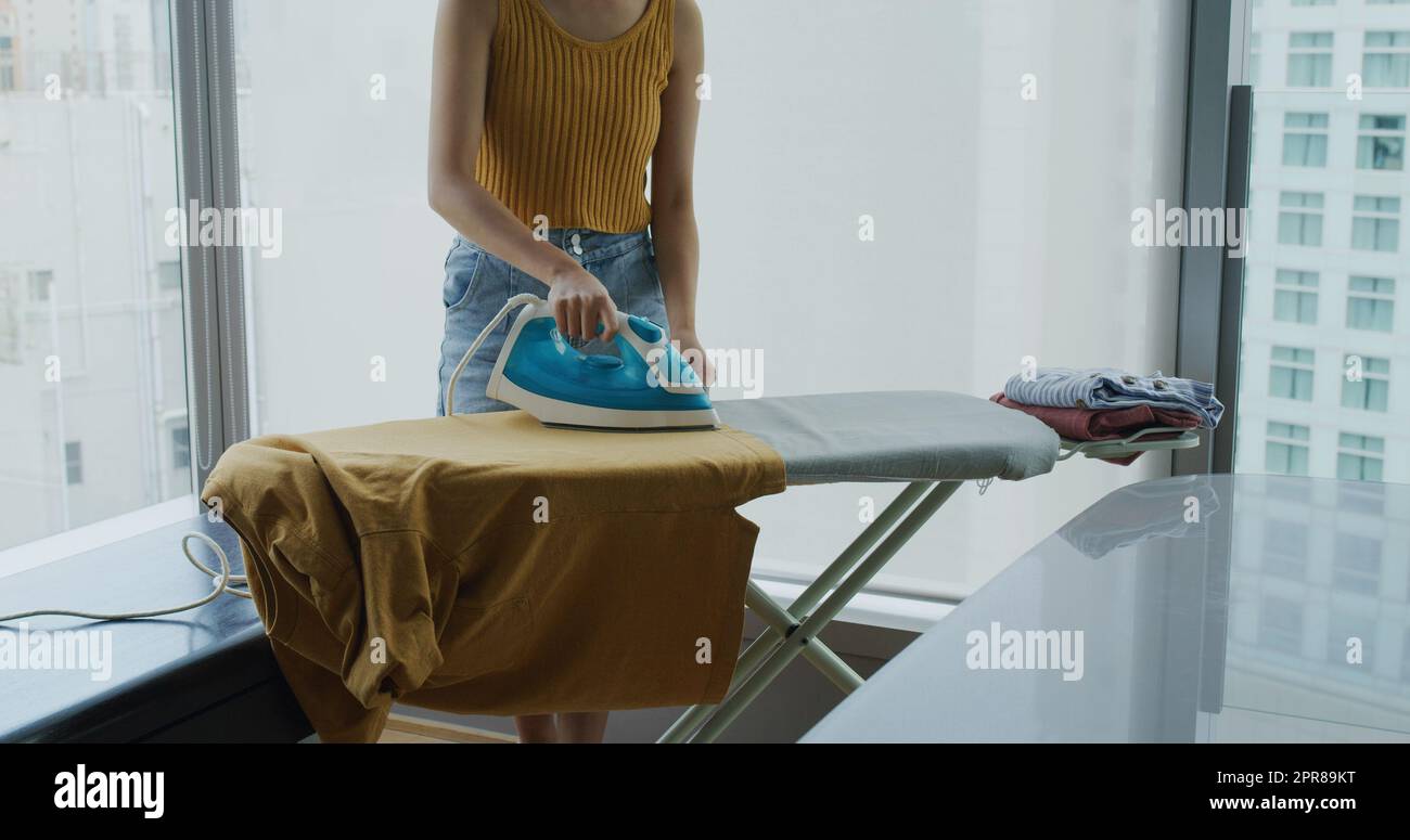 Woman iron clothes with iron on ironing board Stock Photo - Alamy