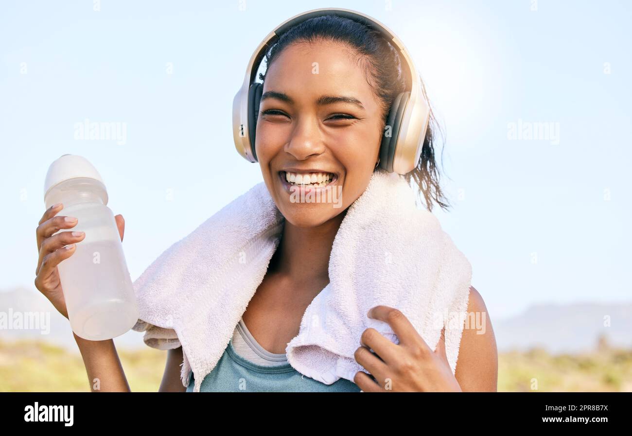 Excited woman smiling and listening to music while out for a workout in ...