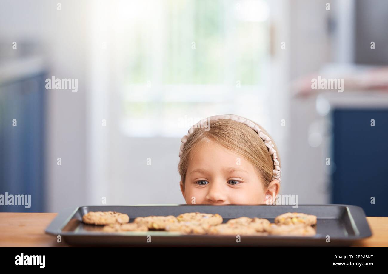 These look delicious. an adorable little girl looking at cookies on a ...