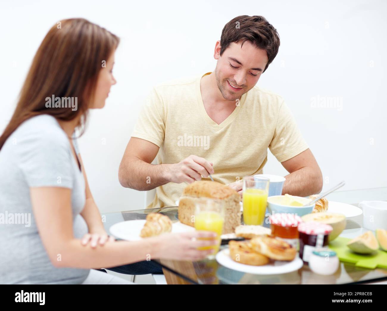 Bonding at breakfast - Expecting parents. A smiling husband having a ...