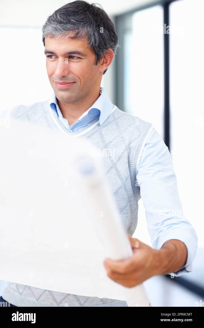 Reviewing blueprint. Portrait of mature male architect reviewing ...
