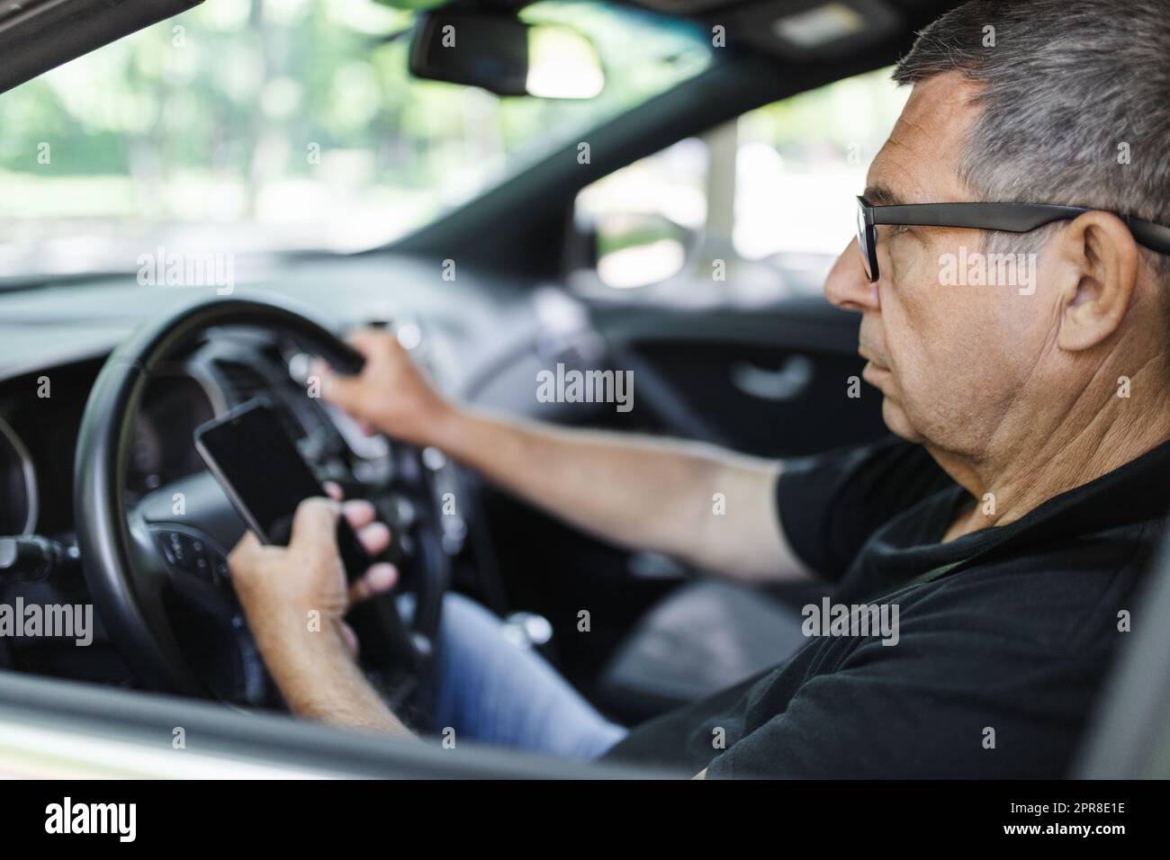 Senior in his 70s driving a car and using his mobile phone Stock Photo ...