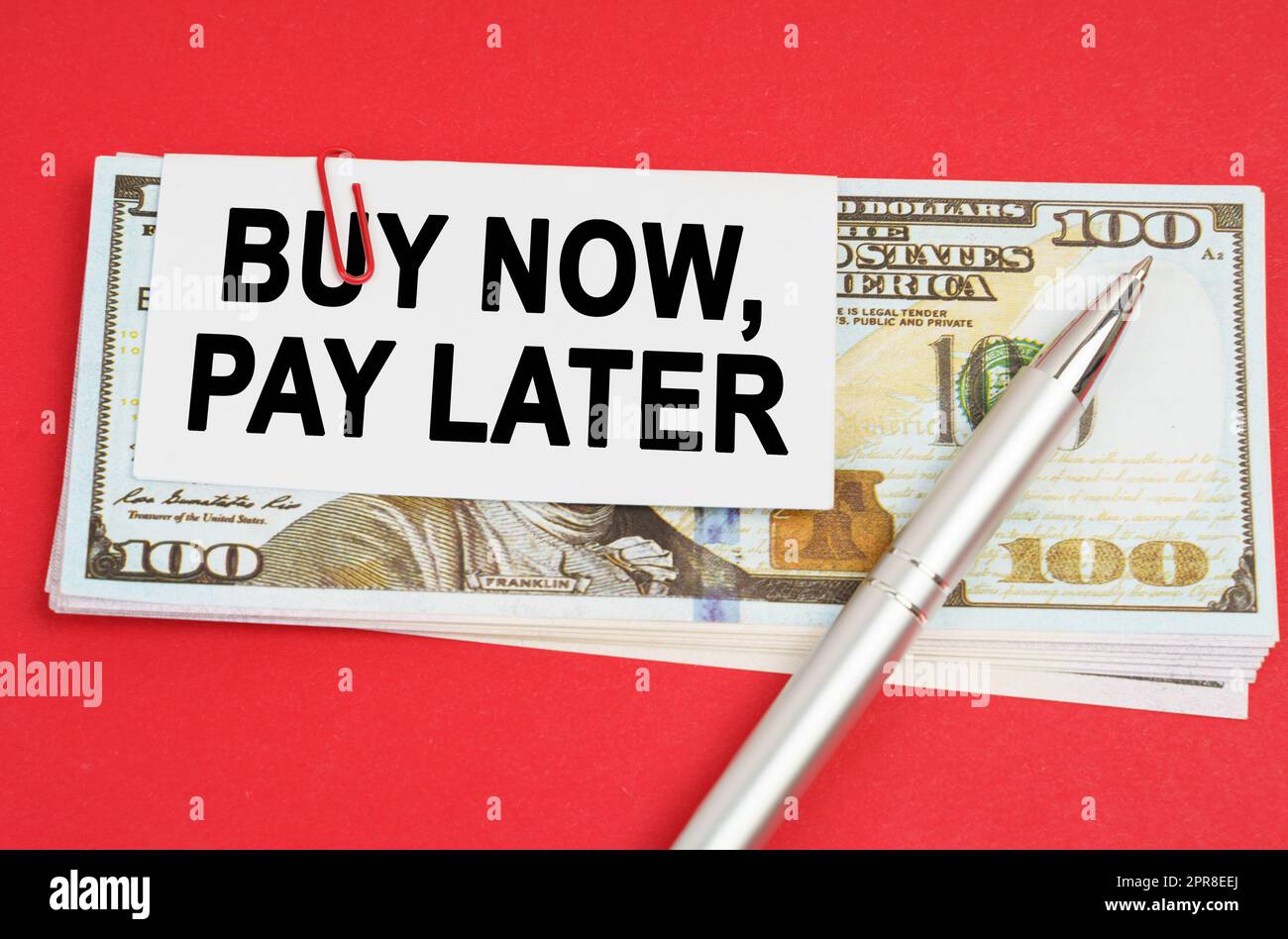 Business concept. On a red surface are dollars on which a pen and paper ...