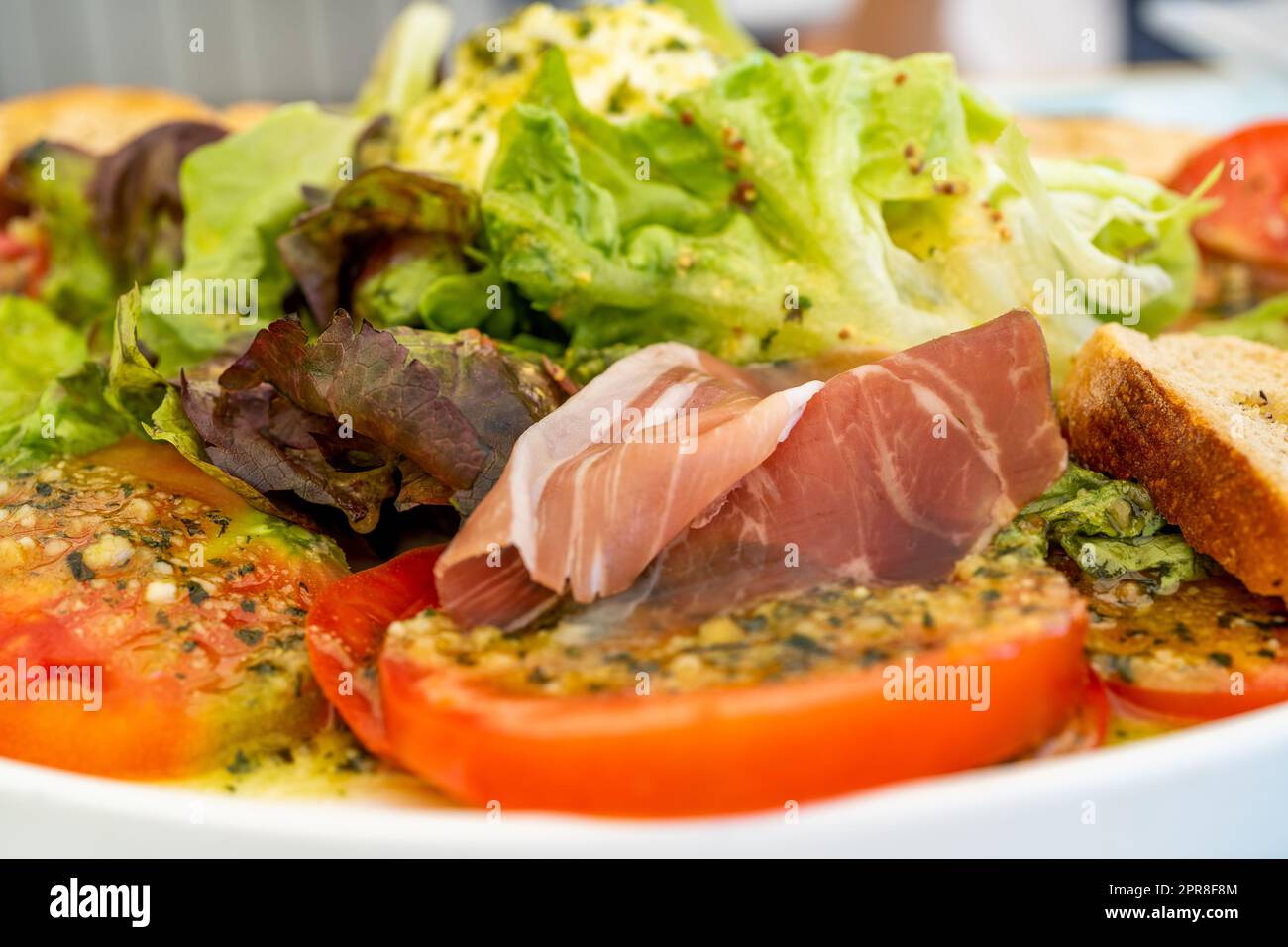 Whole buffalo mozzarella with pesto sauce, salad leaves, tomatoes and ...