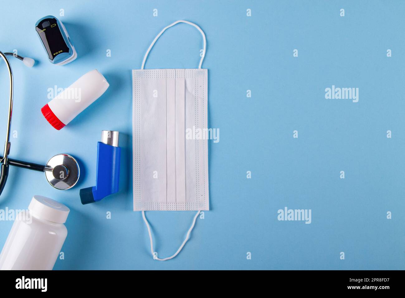 Top view of medical mask, stethoscope, oximeter, bottle of pills and ...