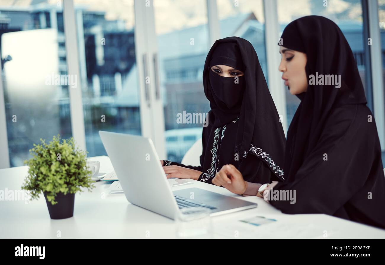 Passing on some of her expertise. two young arabic businesswomen working on a laptop in their ...