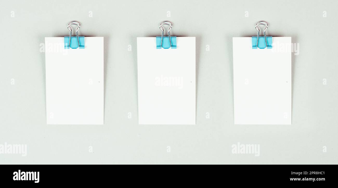Blank white papers with a paperclip on a gray colored background, copy ...
