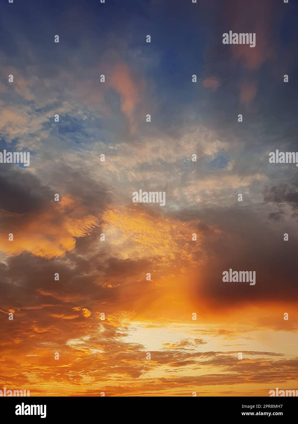 Beautiful sunset sky with colorful orange clouds over the horizon, vertical celestial background ...