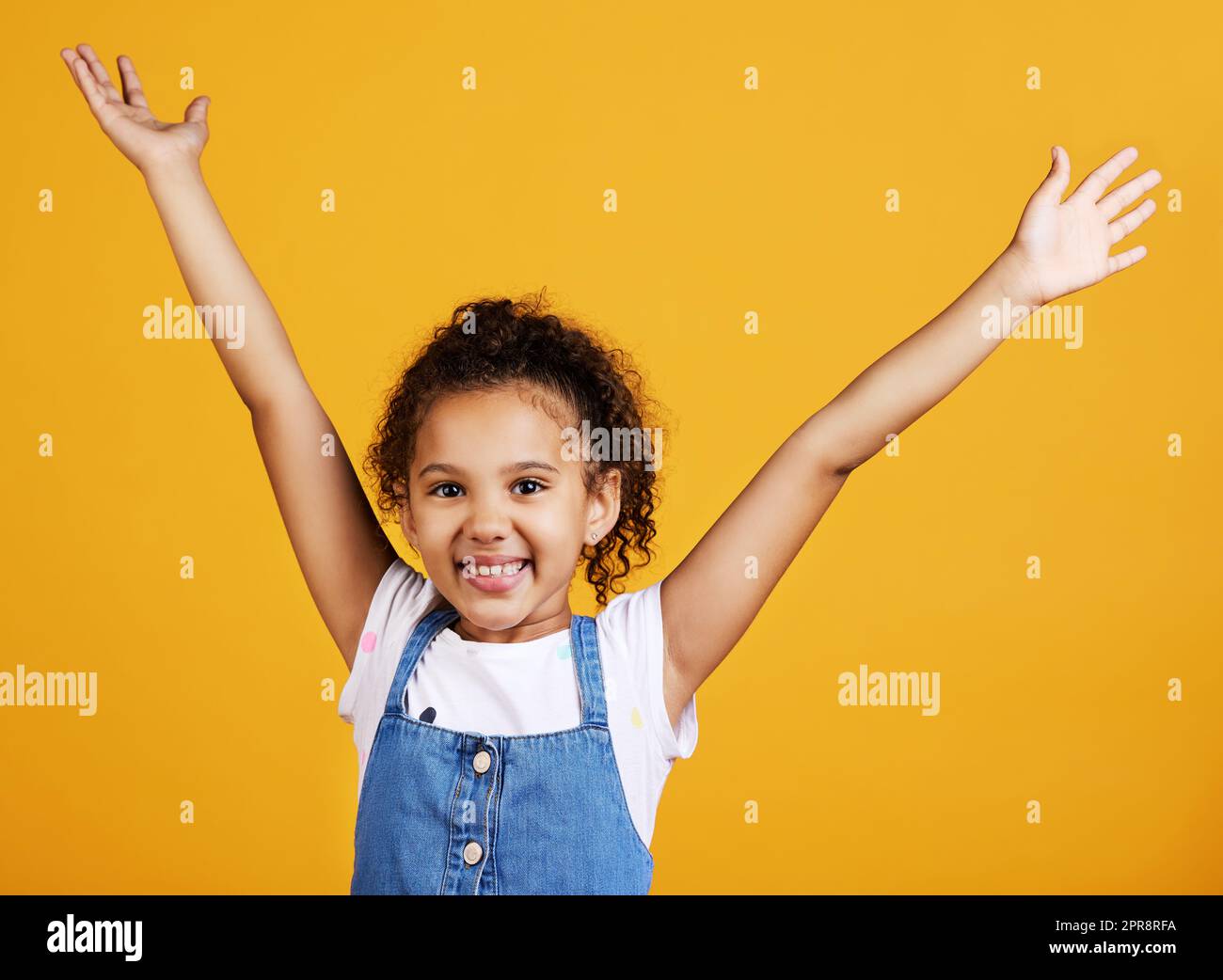 Studio portrait mixed race girl showing surprise with her hands raised ...