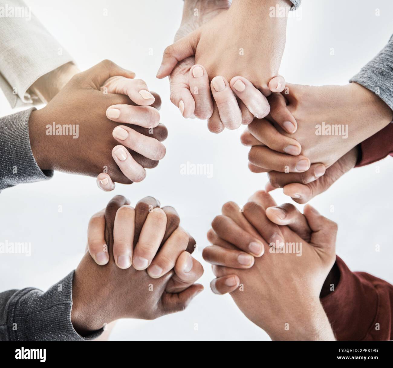 Below close up view of people holding hands in circle shape. A group of ...