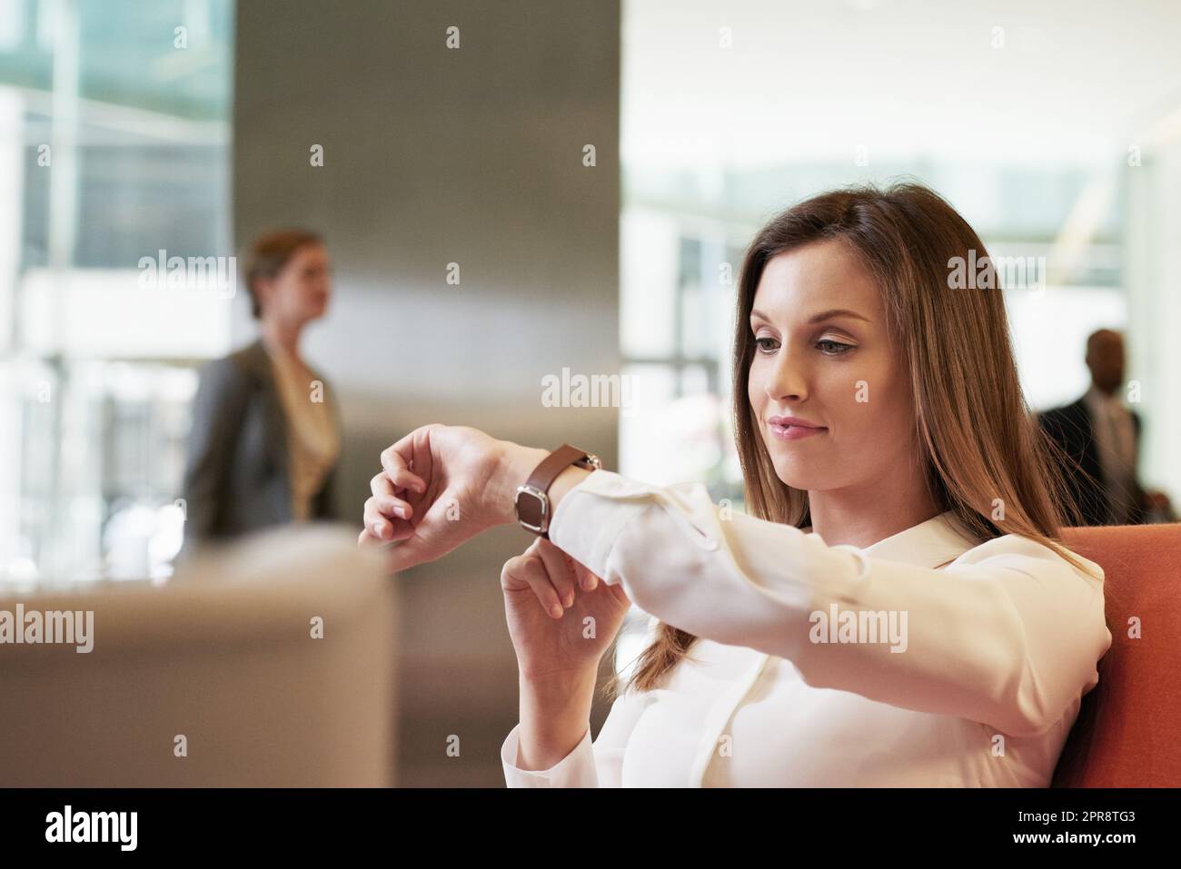 Business woman checking her watch while sitting in airport waiting ...