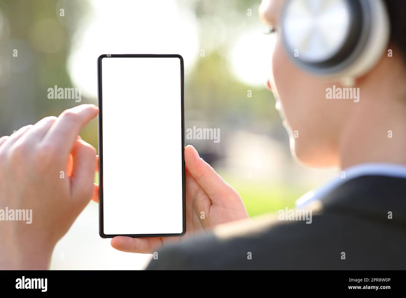 Executive with headphones checking blank phone screen Stock Photo - Alamy