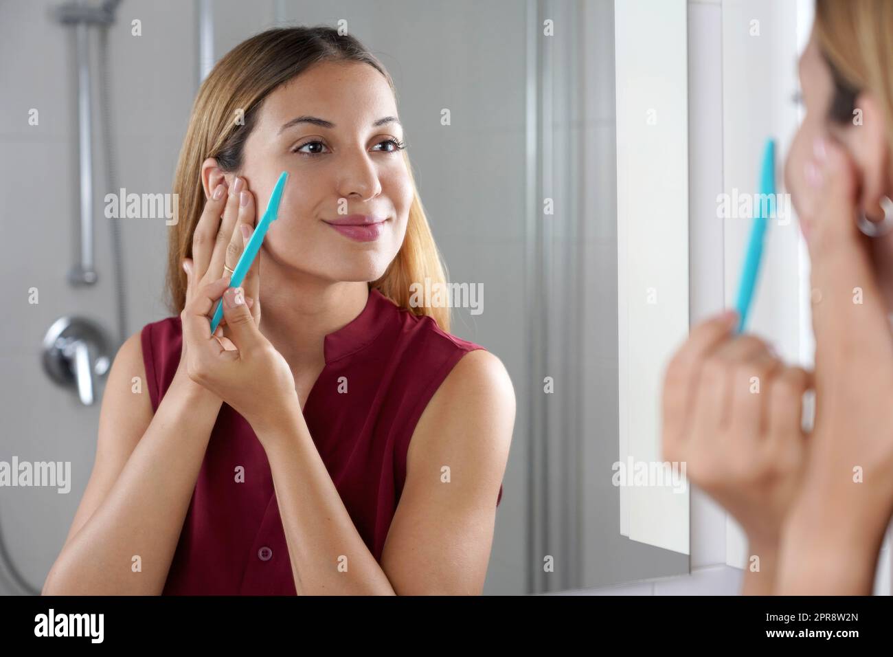 Facial hair removal. Brazilian girl shaving her face by razor at home ...