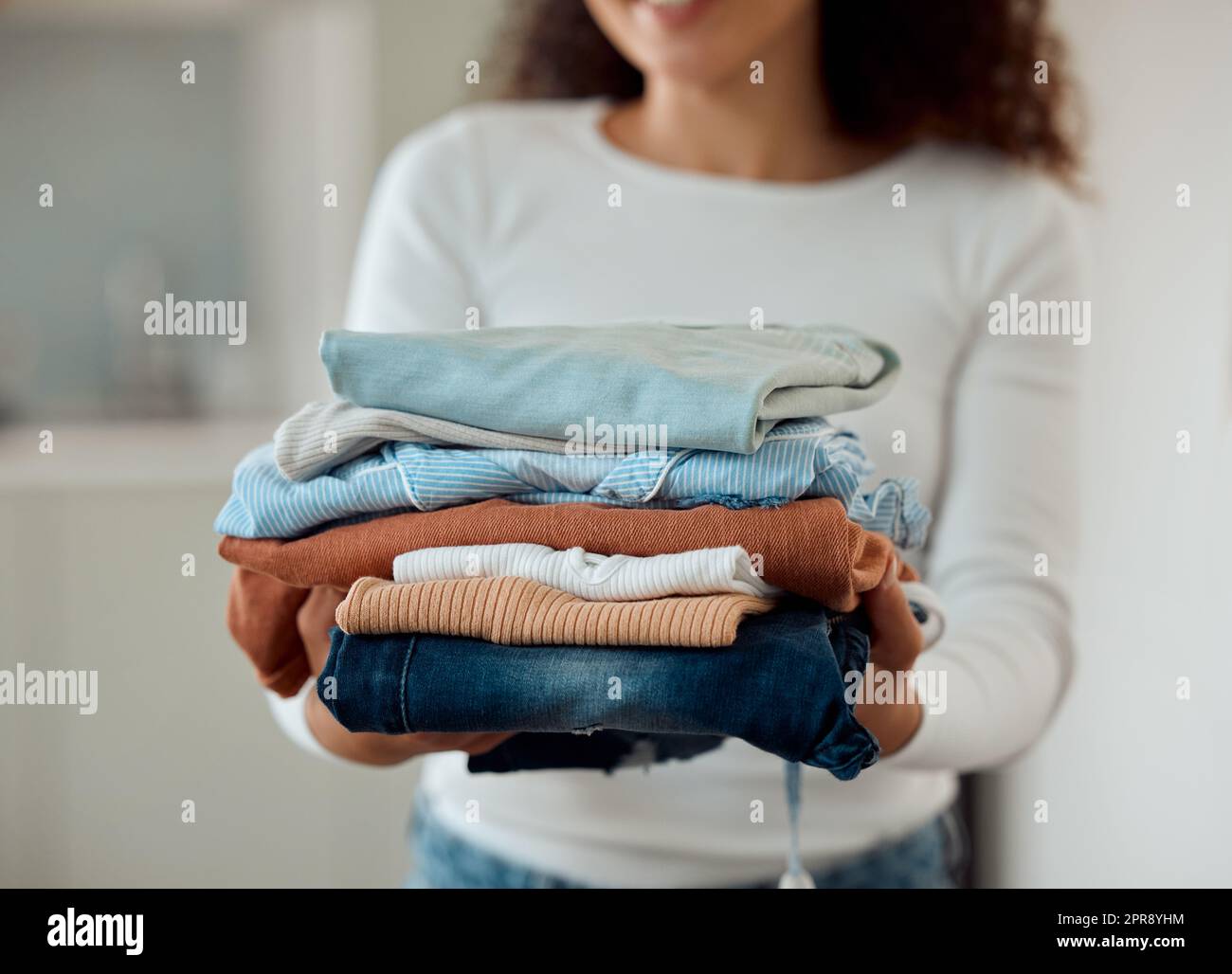 Woman cleaning a pile of laundry. Woman holding a stack of neat, folded ...
