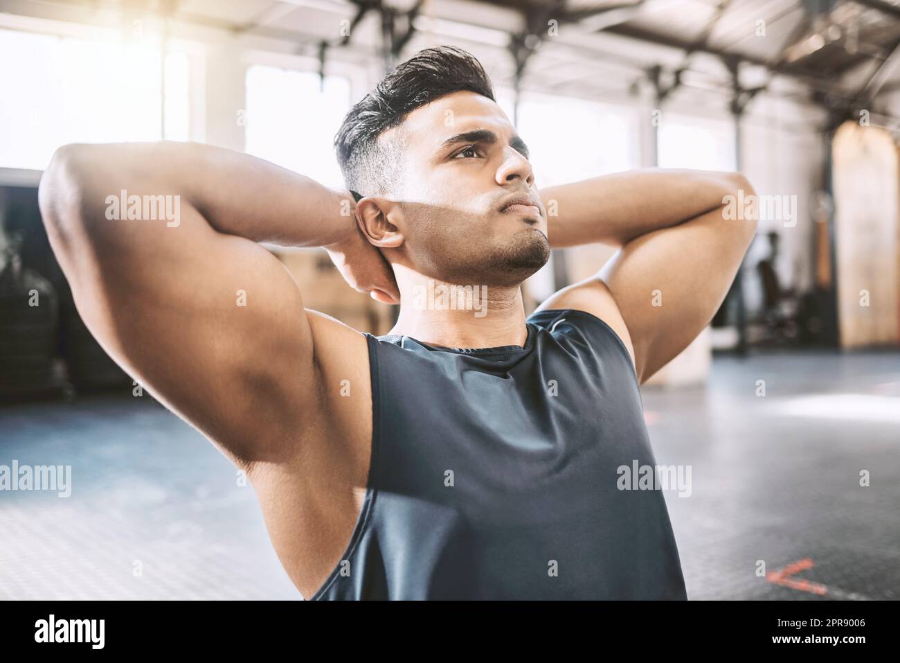 Focused athlete doing sit ups in the gym. Bodybuilder working on his abs and core in the gym ...