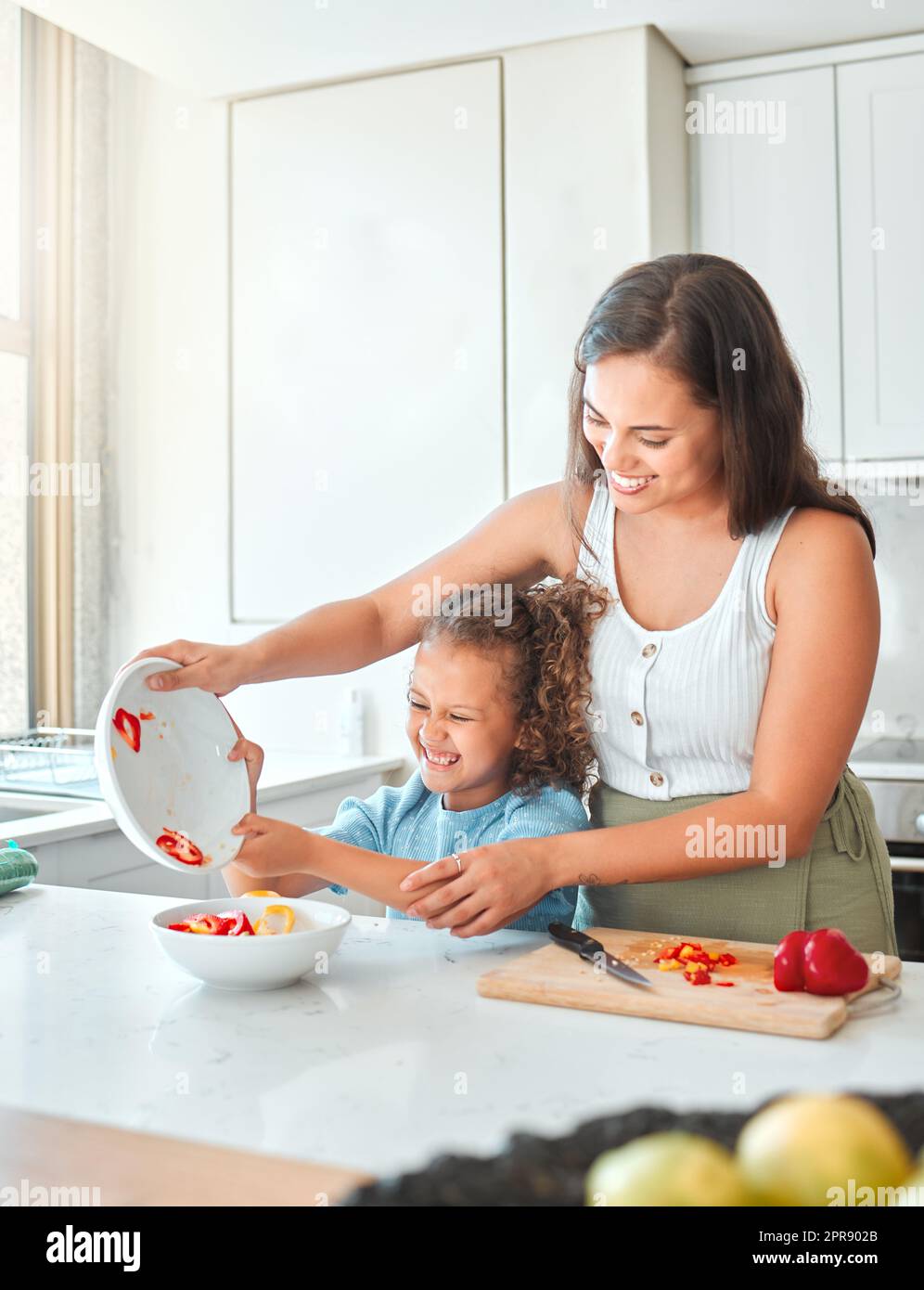 Cheerful mother and little daughter having fun cooking together in the ...