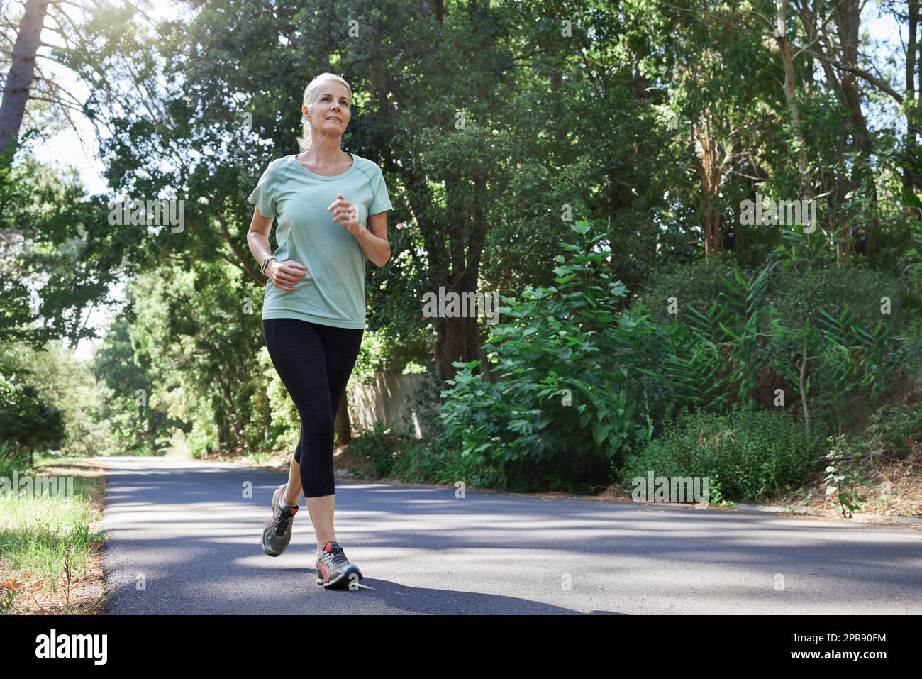 Its never too late to take up running. Low angle shot of a mature woman ...