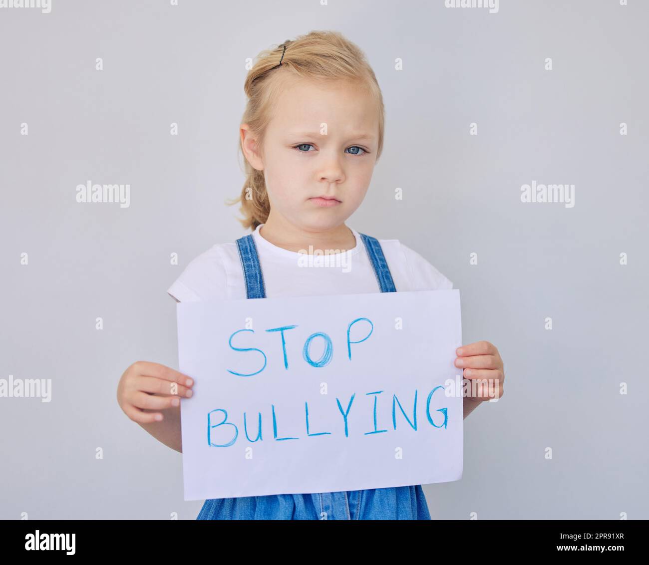 Portrait of sad little girl holding up stop bullying sign. Adorable ...