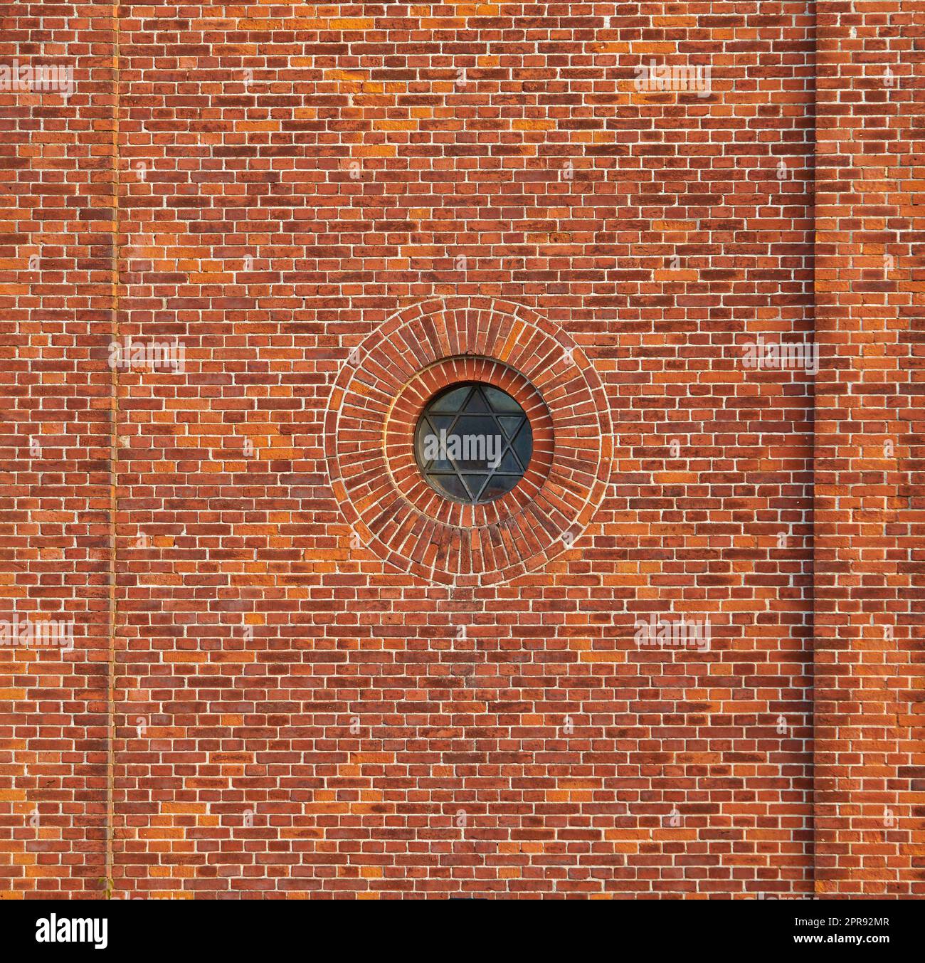 Wall of a jewish synagogue with round window on an old red brick house ...