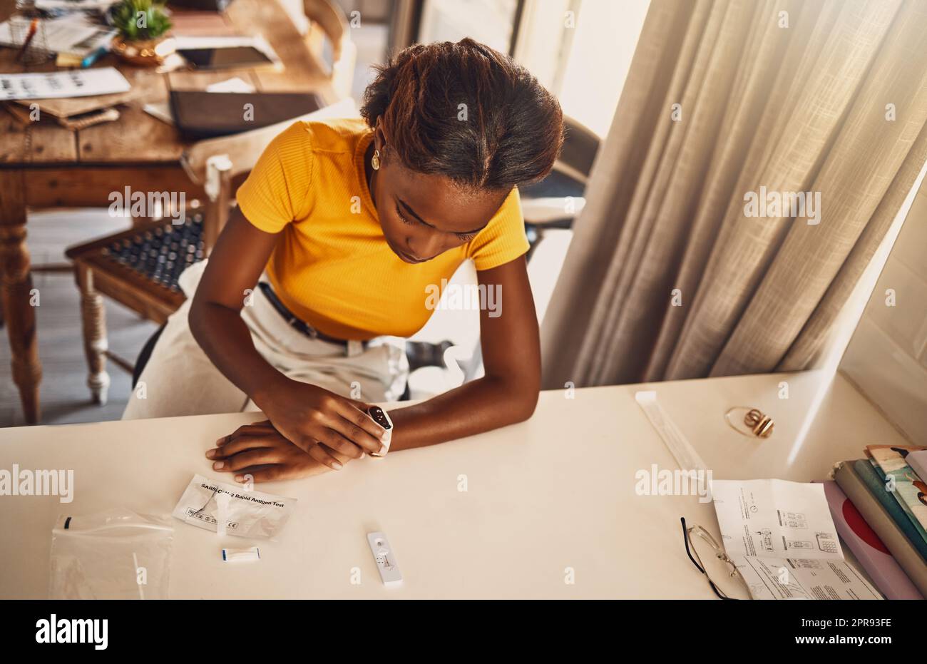 Black woman looking at time while waiting for results of a home test ...