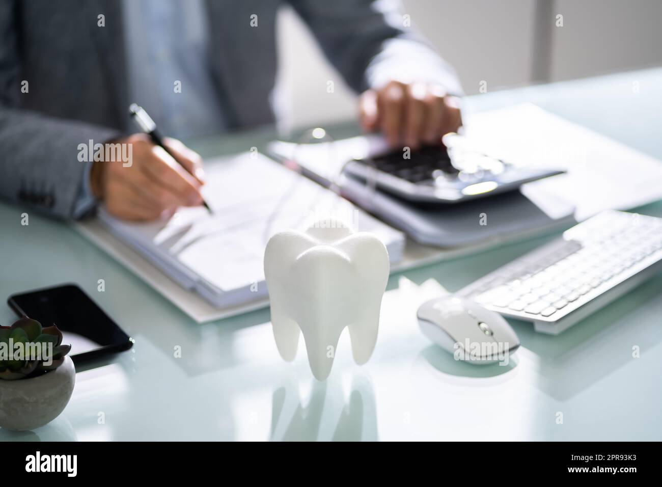 Tooth In Front Of Businessperson Calculating Bill Stock Photo - Alamy