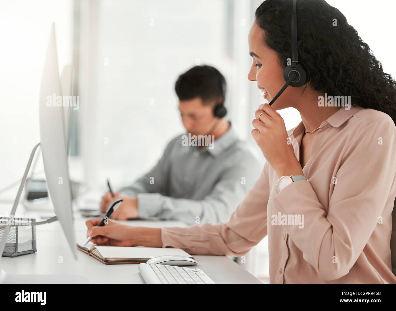 Ill make a note of that. two young call center agents working in an ...
