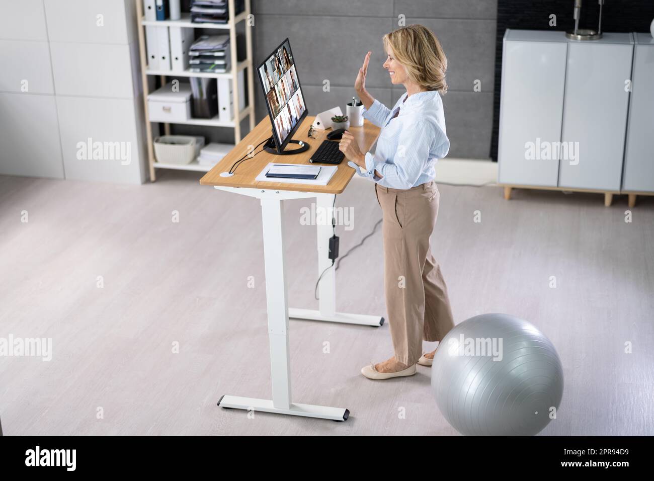 Woman Using Adjustable Height Standing Desk In Office Stock Photo - Alamy