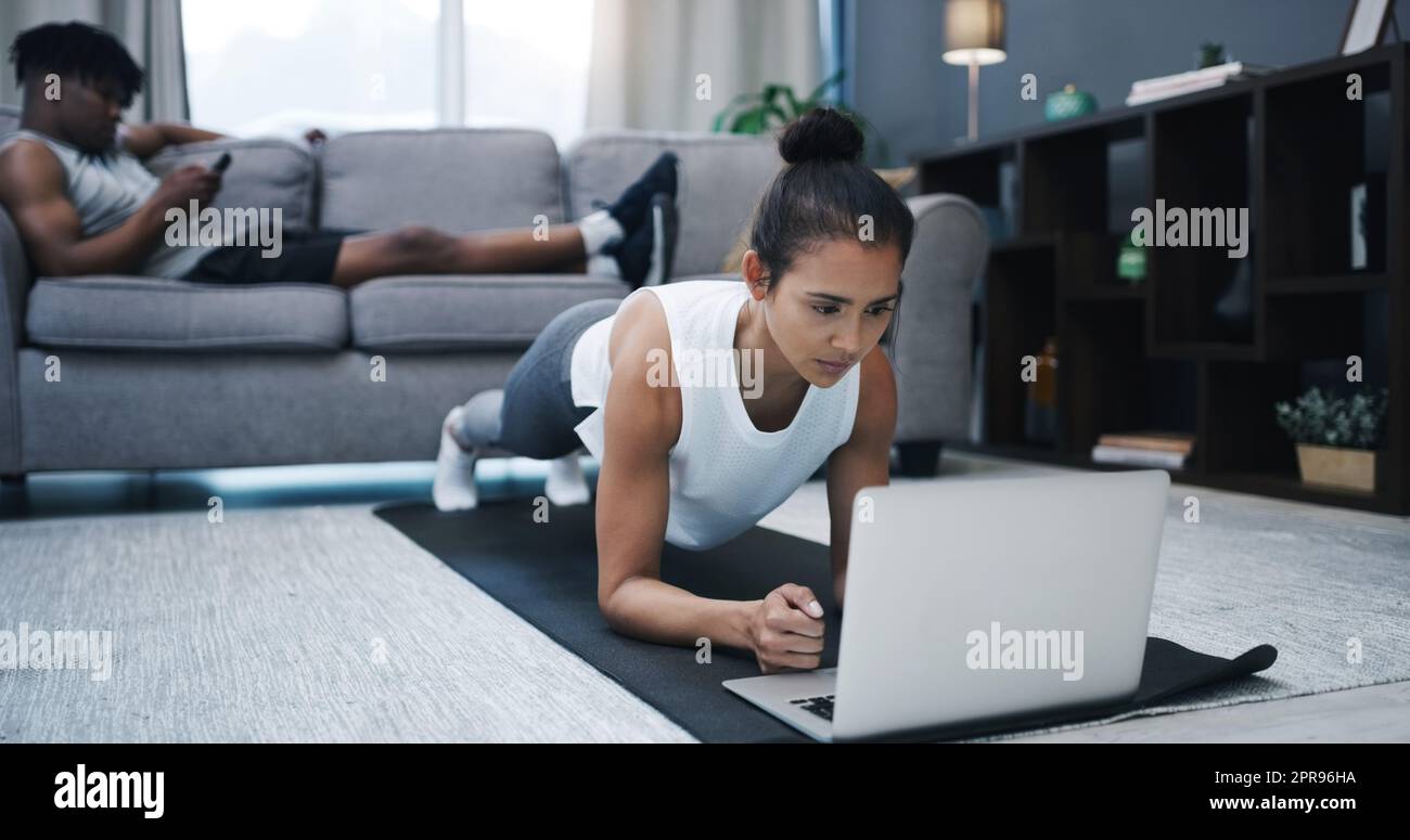 I love these virtual classes. a young woman looking at her laptop screen while exercising at ...