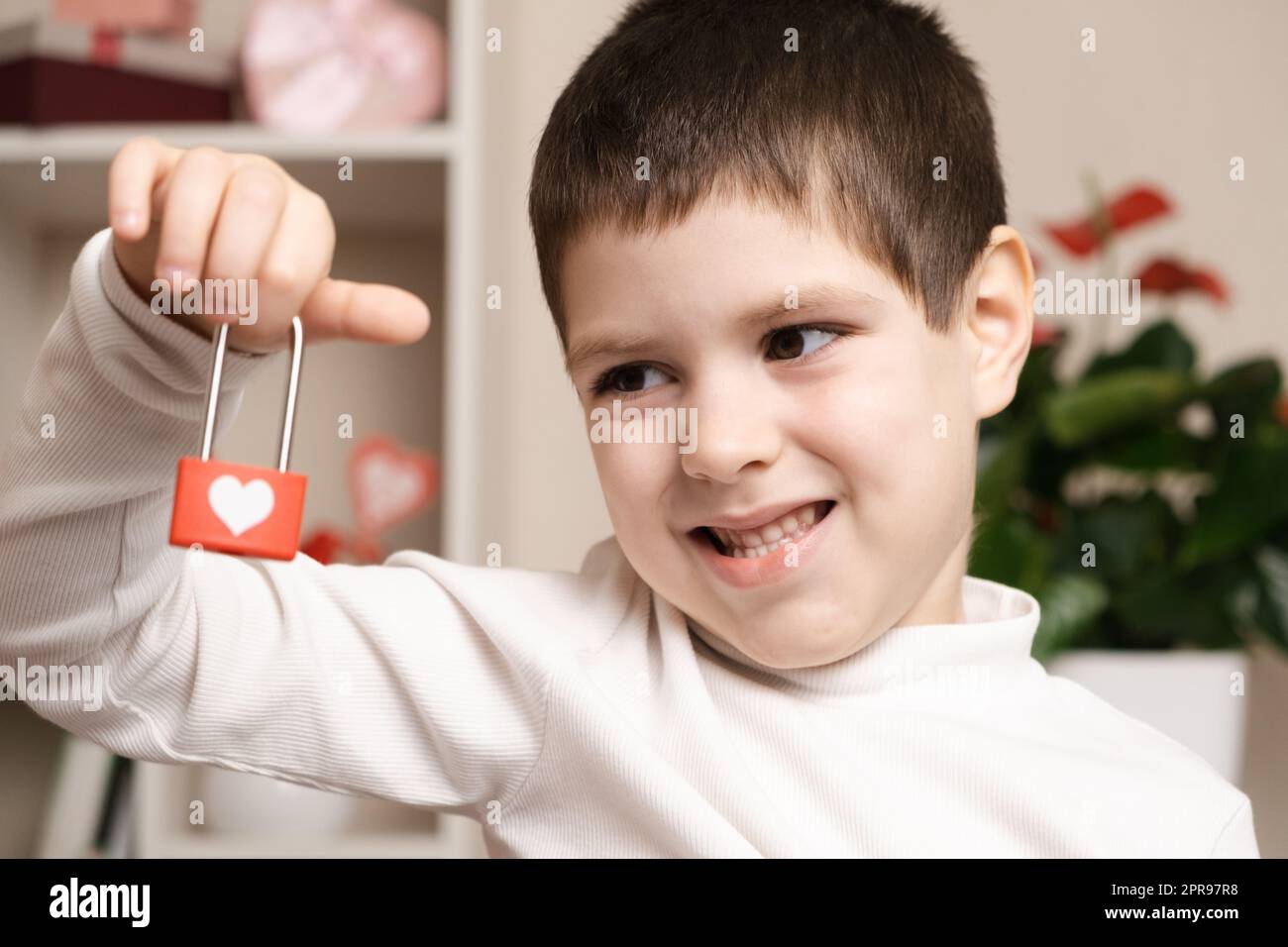 A 5 year old cute boy holds a lock with heart and smiles. Valentine's ...