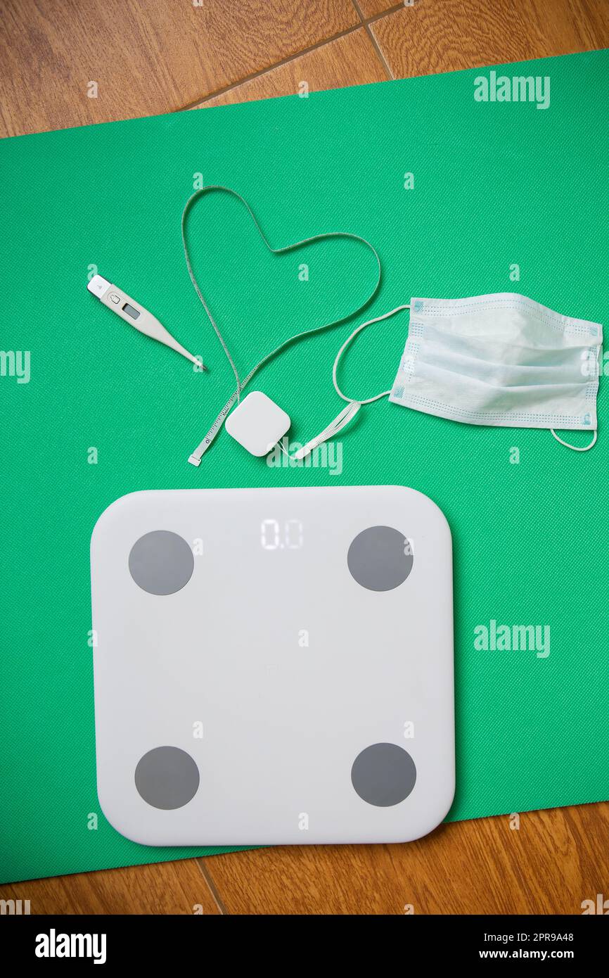 On a green background are electric scales, centimeter, medical mask ...