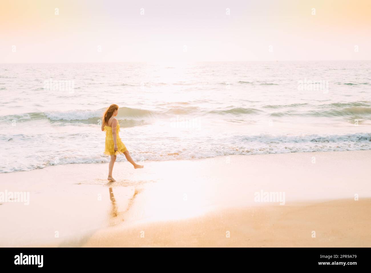 Goa, India. Young Caucasian Woman In Yellow Dress Walking Along ...