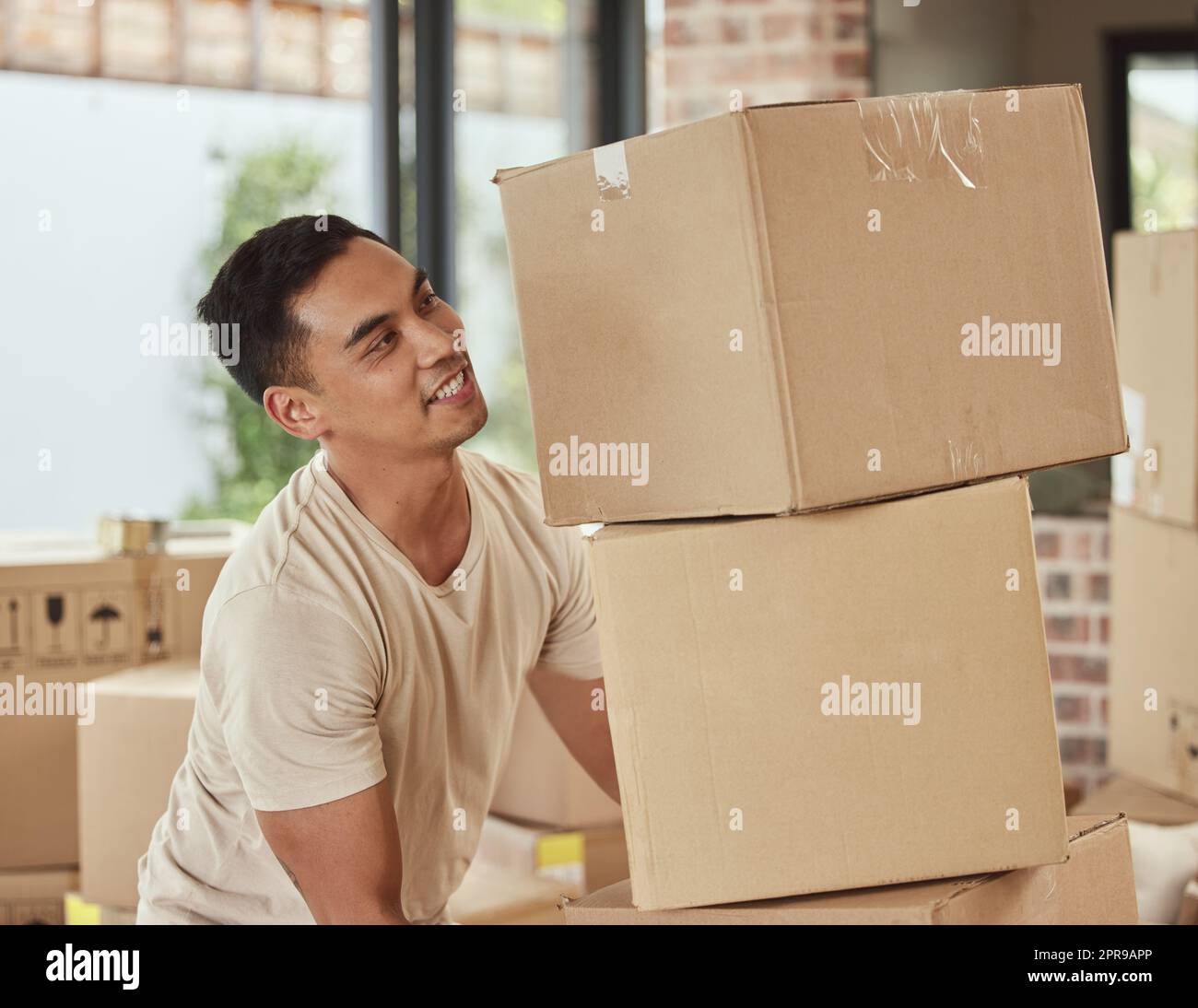 Getting settled into his new home. a man carrying boxes into his new ...