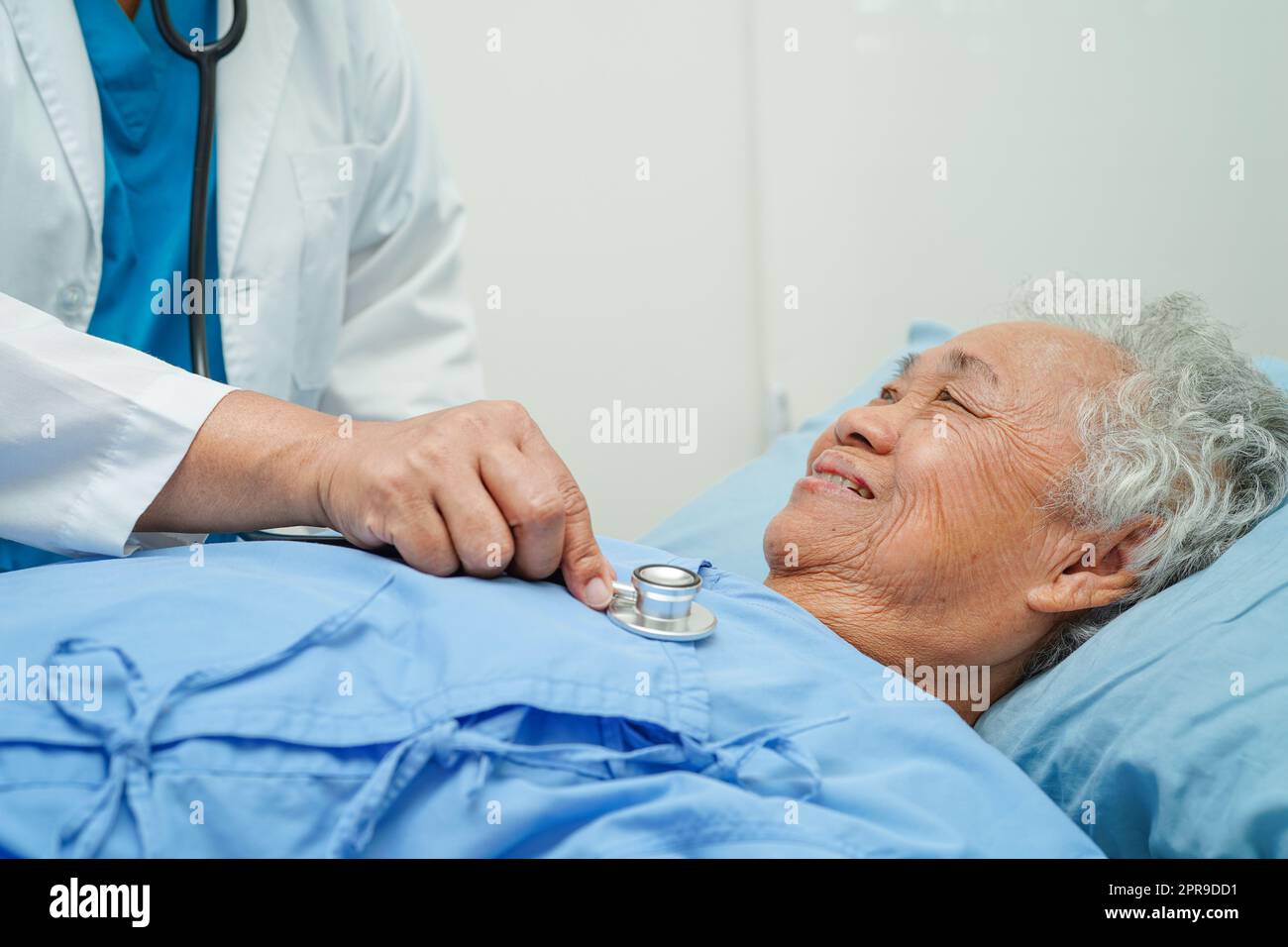 Doctor taking care, help and encourage Asian elder senior woman patient ...