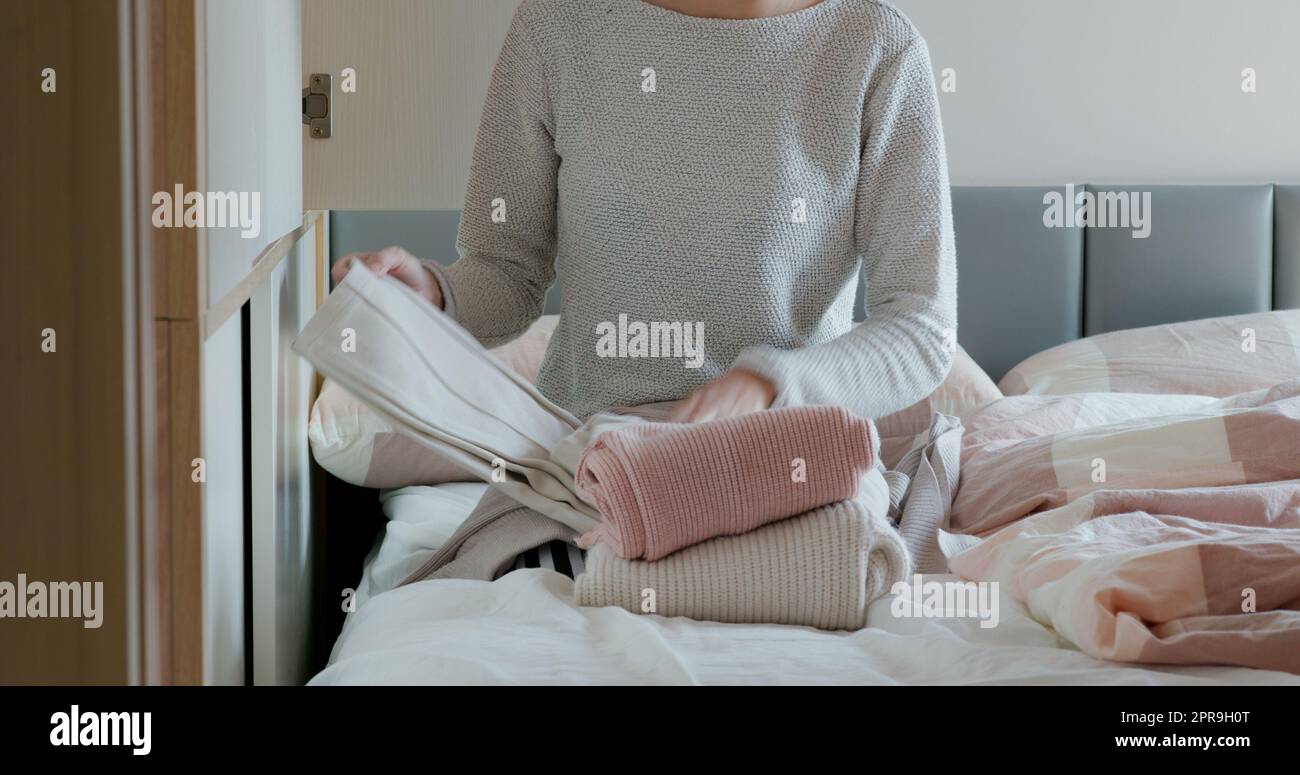 Woman fold with her clothes and put into wardrobe Stock Photo - Alamy