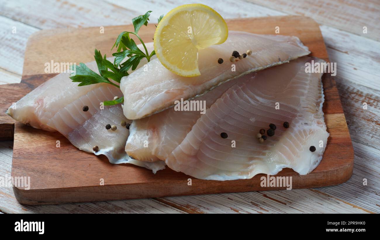 Fresh tilapia fish fillet sliced for steak or salad with herbs spices ...