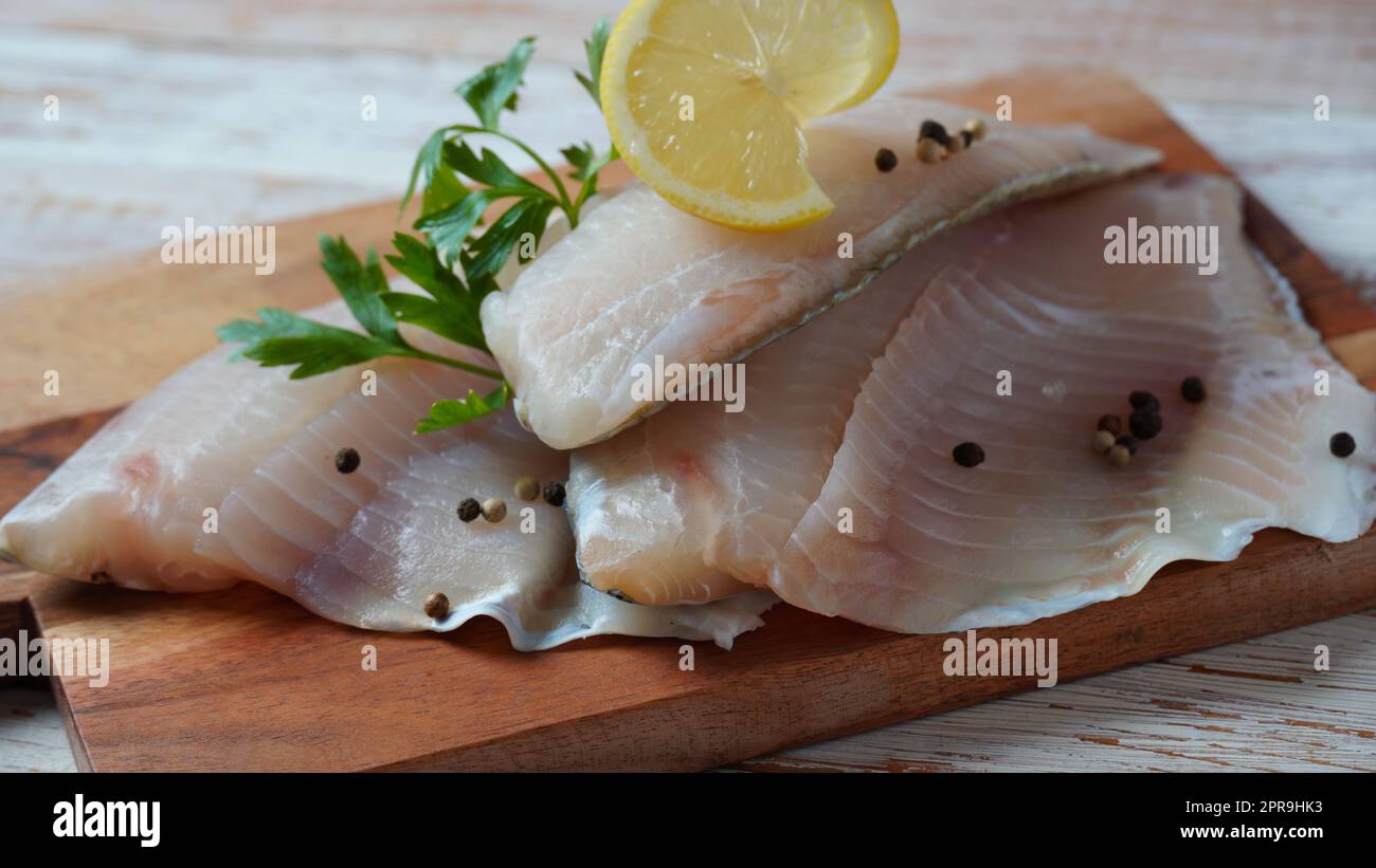Fresh tilapia fish fillet sliced for steak or salad with herbs spices ...