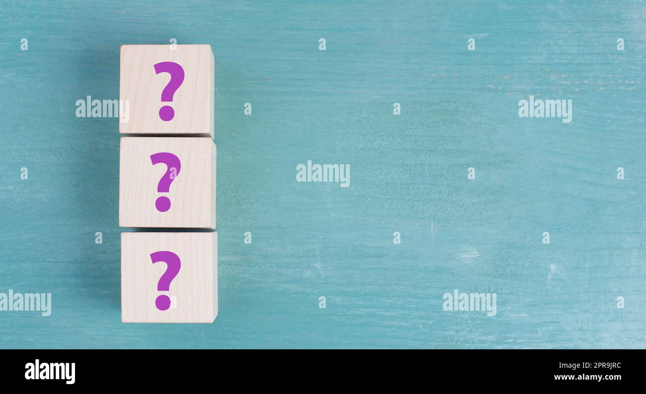 Three wooden cubes with question marks in purple color, searching for ...