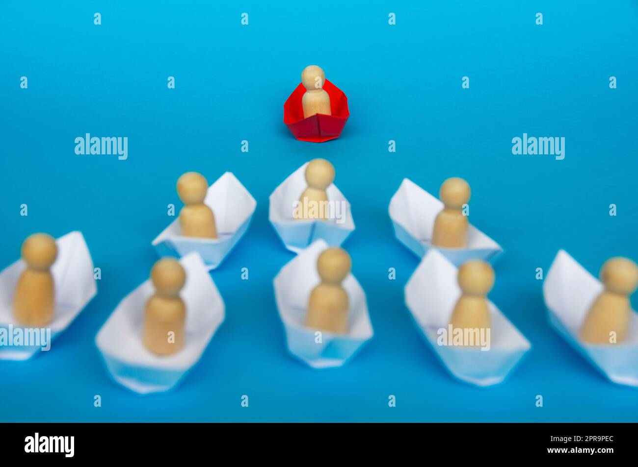 Leadership Concept - Wooden figure on red paper ship origami leading ...