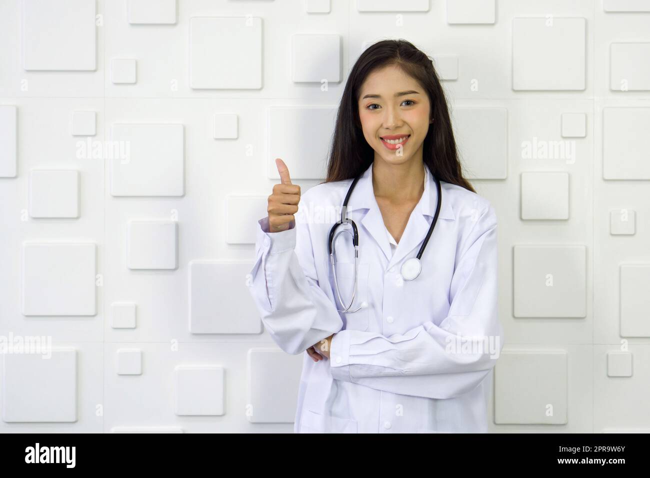 Young asian doctor in white gown and stethoscope stand with finger ...