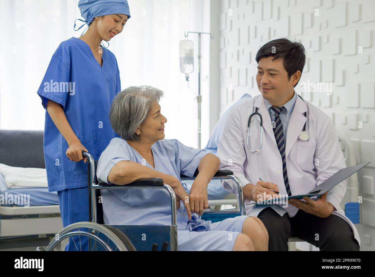 Young nurse push a wheelchair of the elderly patient while asian doctor ...